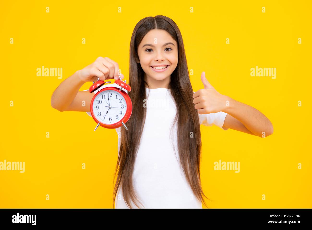 Punctual teen girl checking time. Child with alarm clock showing time ...