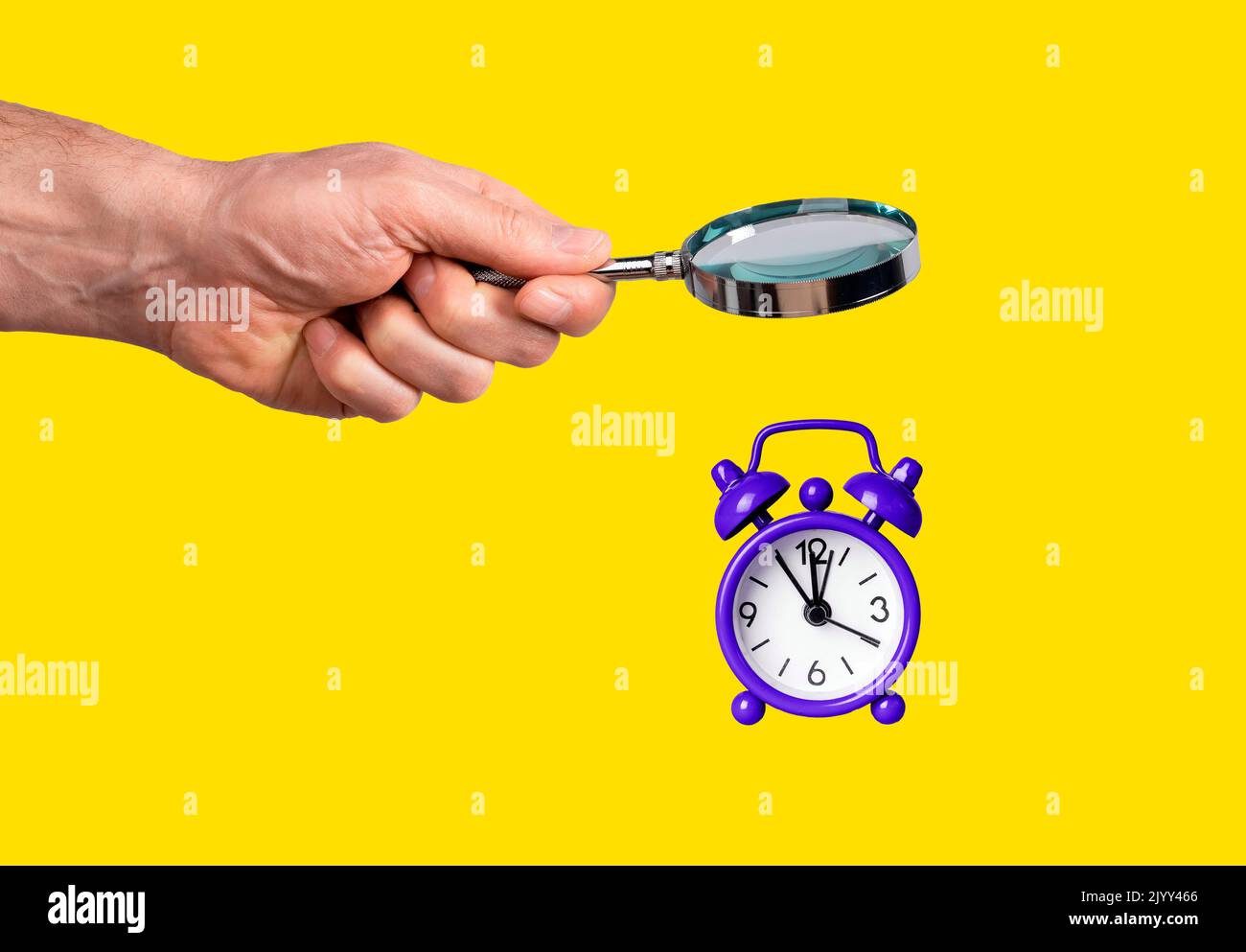 Hand holding magnifying glass over alarm clock. Time management ...