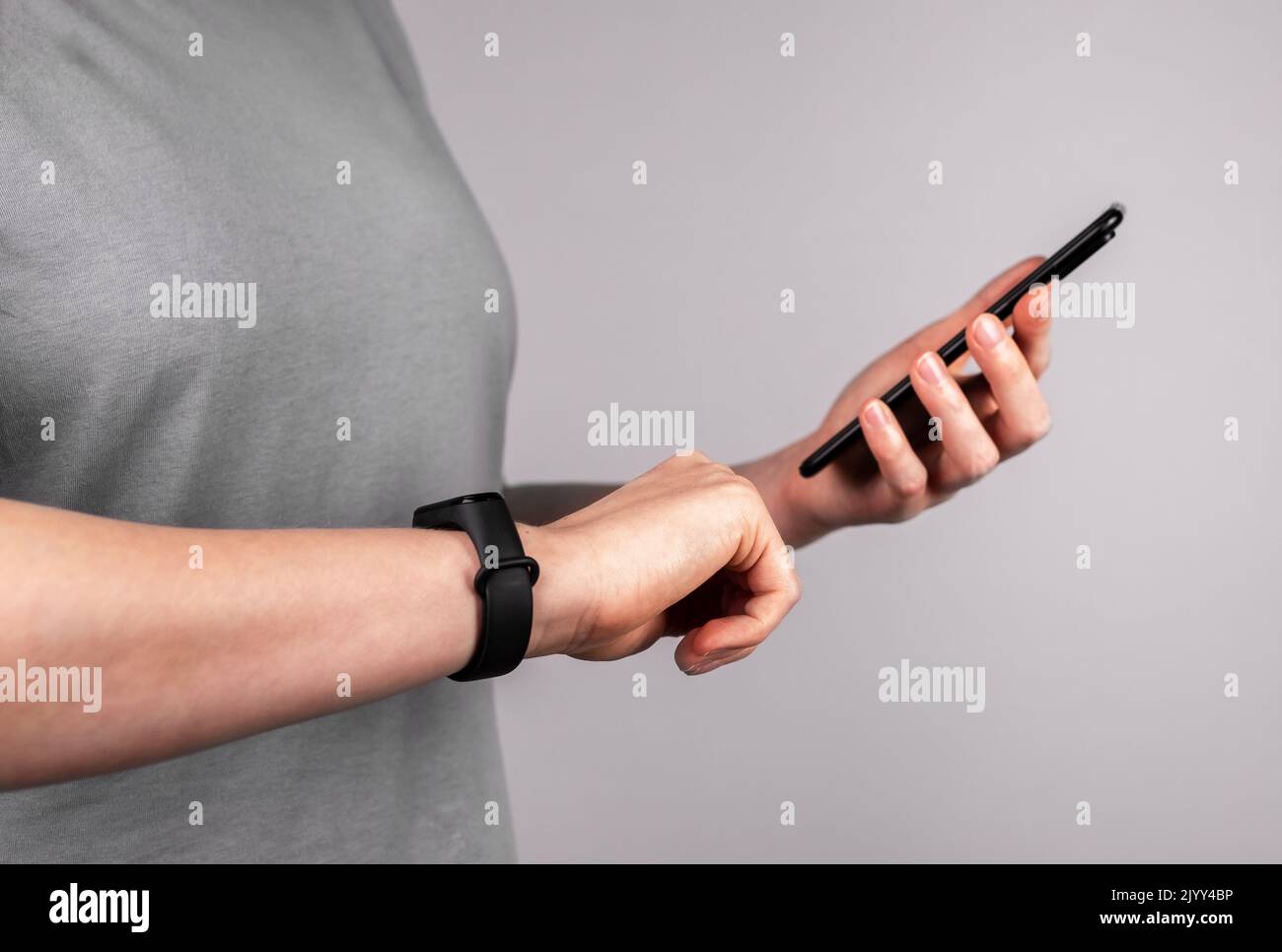 Woman with fitness bracelet at wrist using mobile app at phone for ...