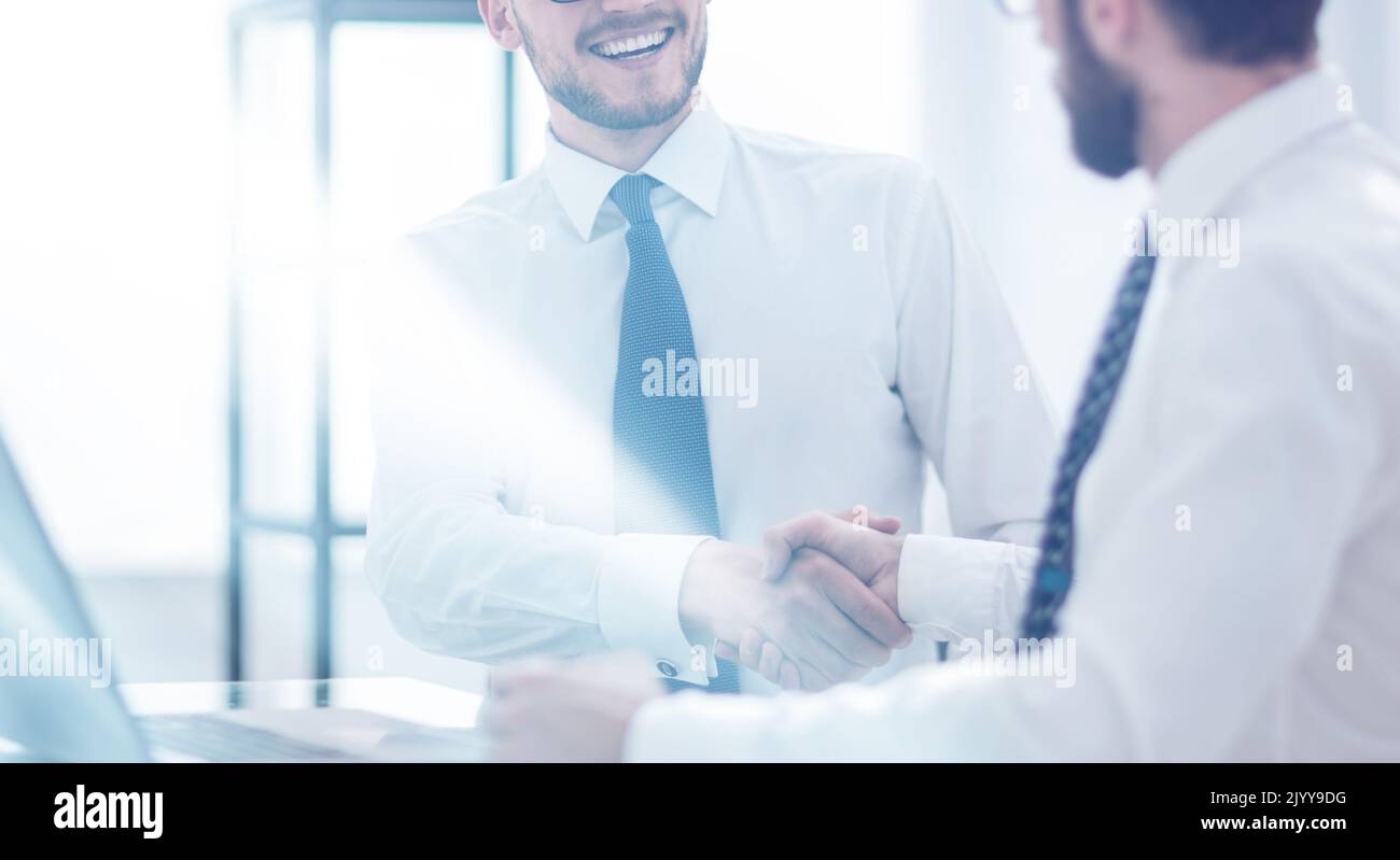 side view.the handshake of the employees sitting behind a Desk Stock ...