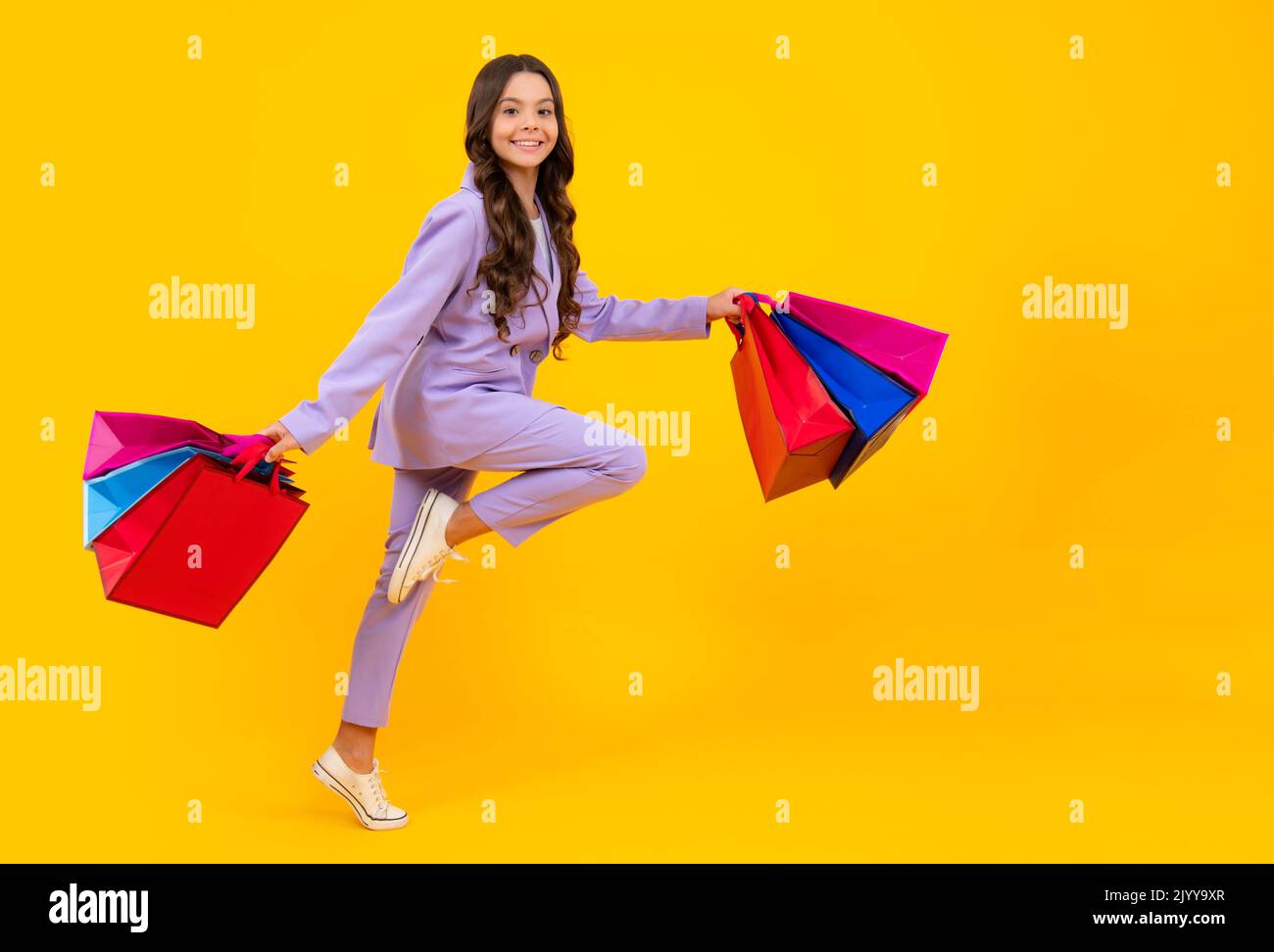 Child girl hold shopping bag enjoying sale isolated on yellow ...
