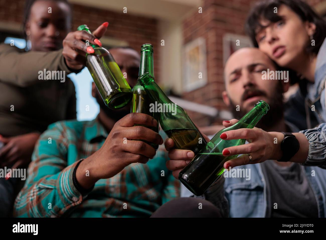 Multiethnic group of friends saying cheers and clinking beer bottles to ...