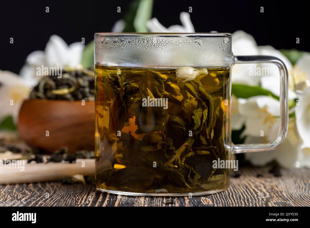 Brewed green tea with jasmine on the table, dried tea leaf for brewing ...