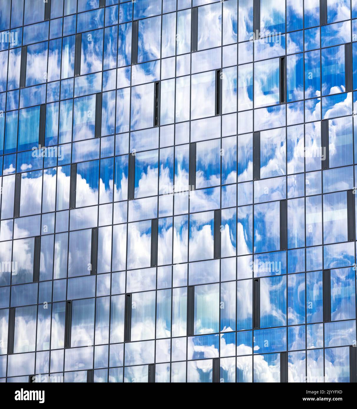 Reflection in the building blue sky with light clouds in windy weather ...