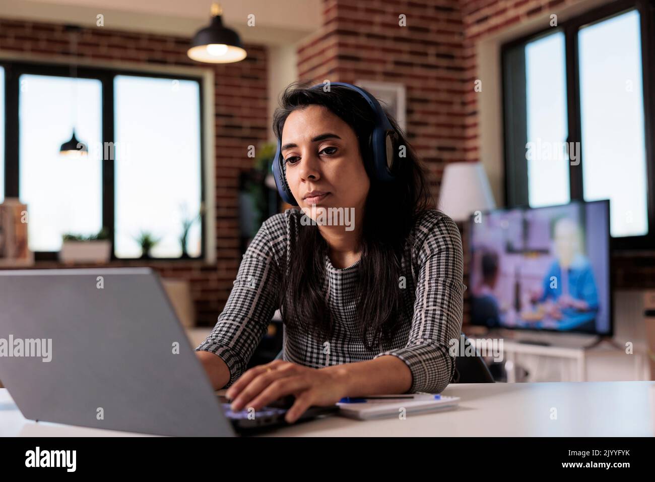 Employee listening to music on headphones and working on report with ...