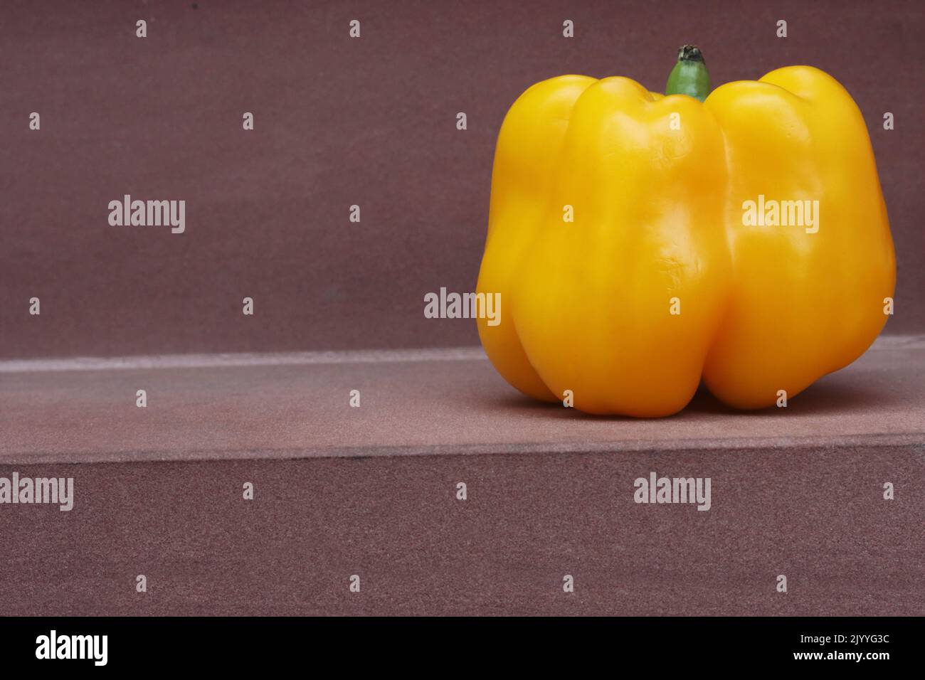 Big Yellow Paprika Sweet Pepper with green stem laying on the brown ...