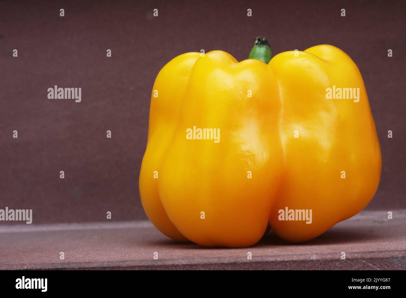 Big Yellow Paprika Sweet Pepper with green stem laying on the brown ...