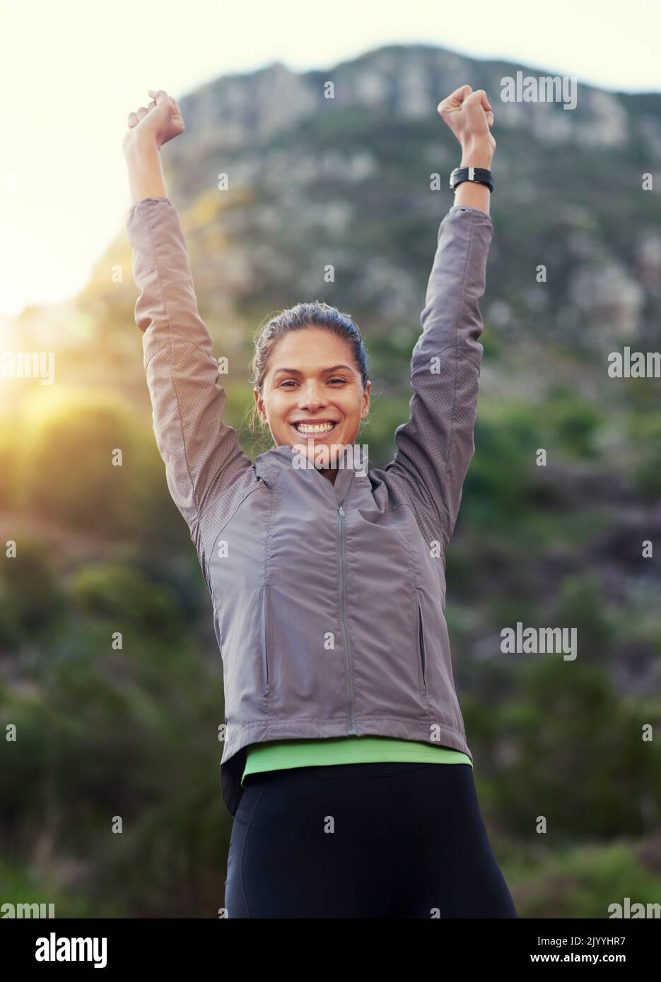 Personal best. a young woman with her arms raised in vicotry while out ...