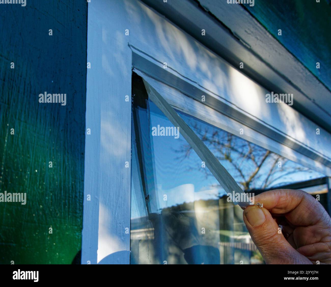 Painting window frames using masking tape, renovating an old wooden ...