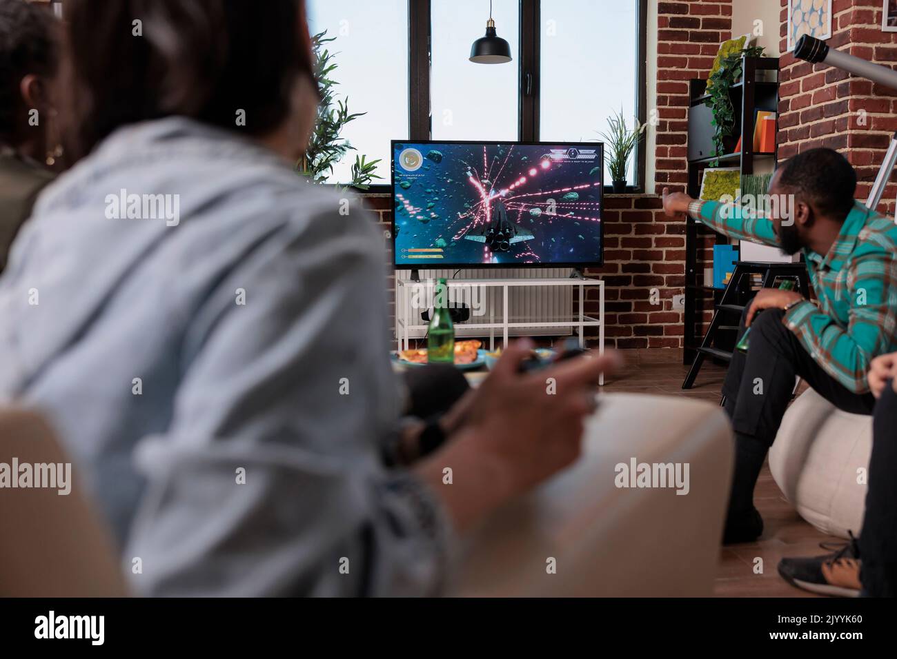 Group of men and women having fun with shooter video games on tv, using ...