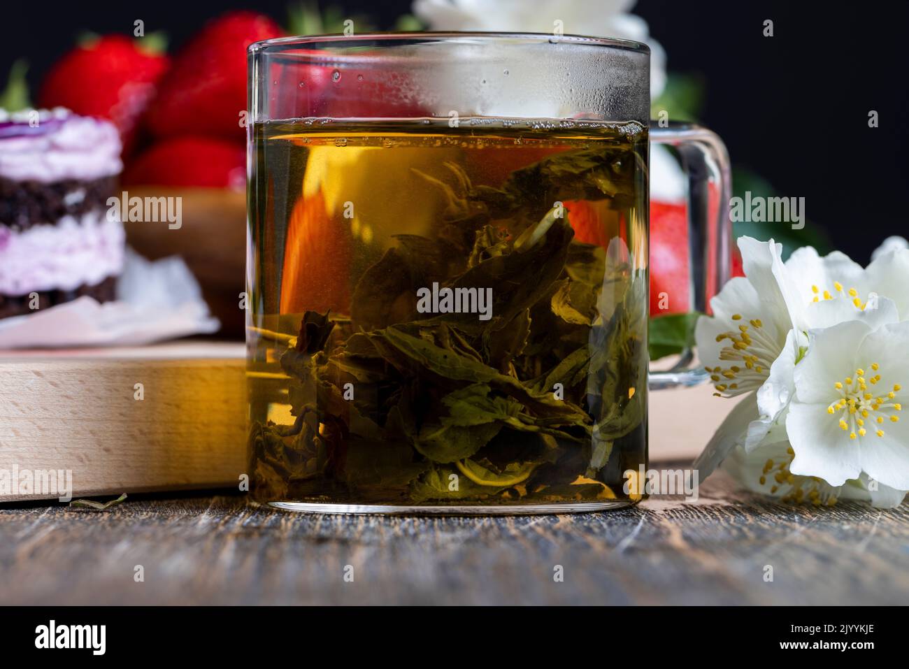 Brewed green tea with jasmine on the table, dried tea leaf for brewing ...