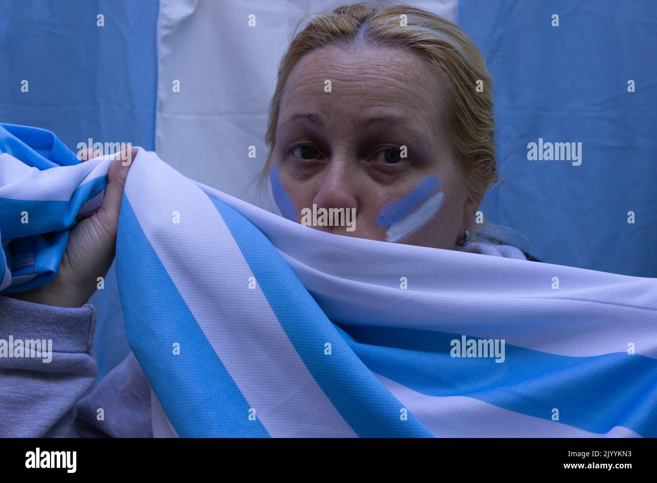 Blonde woman with a flag and face painted in the colors of Argentina ...