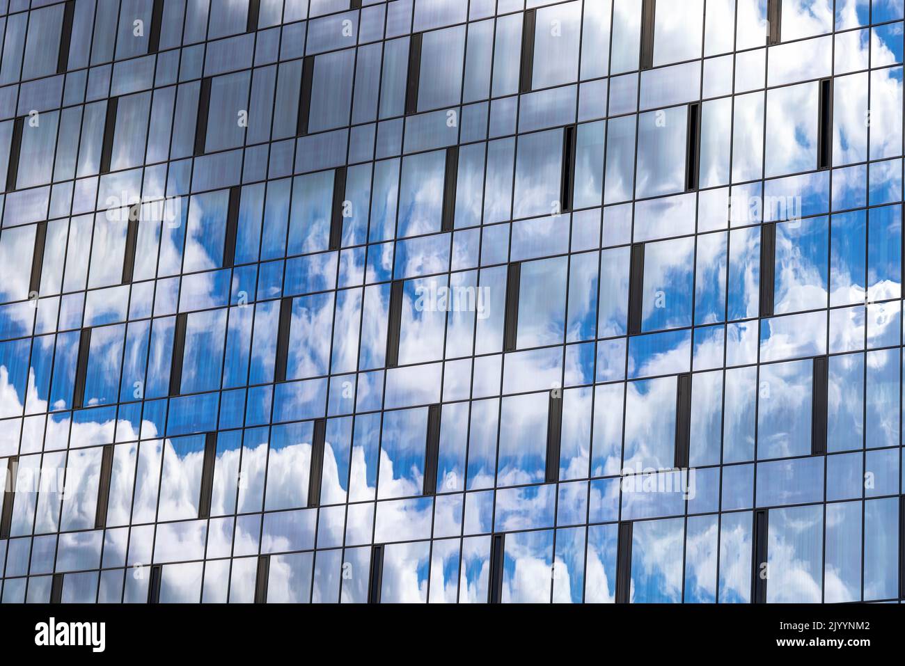 Reflection in the building blue sky with light clouds in windy weather ...