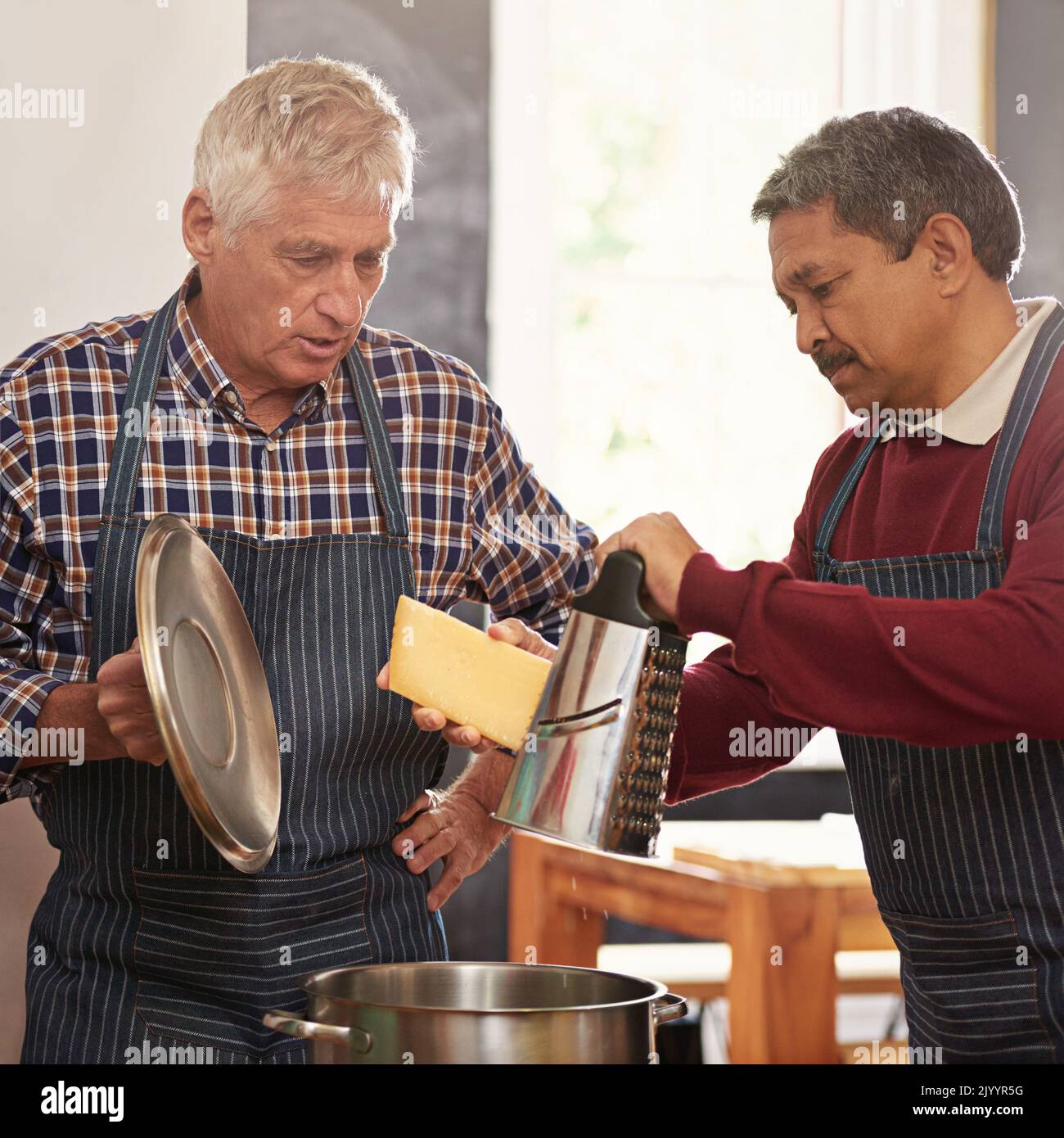 Its all about the cheese. two senior men cooking in the kitchen Stock ...