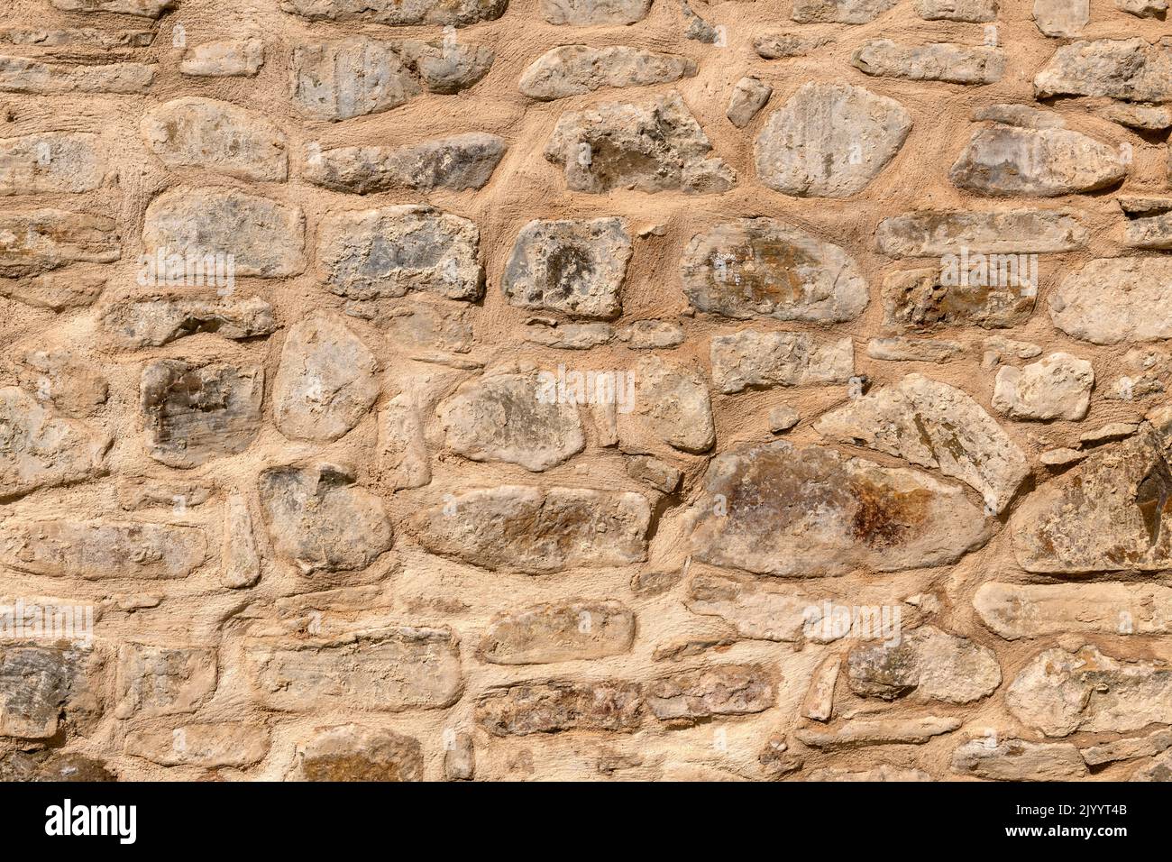 Close up of old stone wall with thick grout and rough textured surface ...