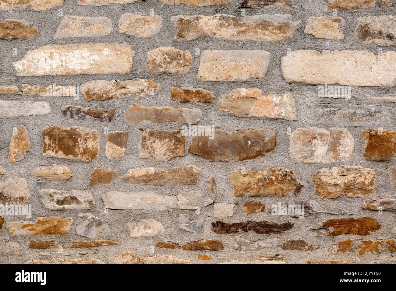Close up of old stone wall with thick grout and rough textured surface ...
