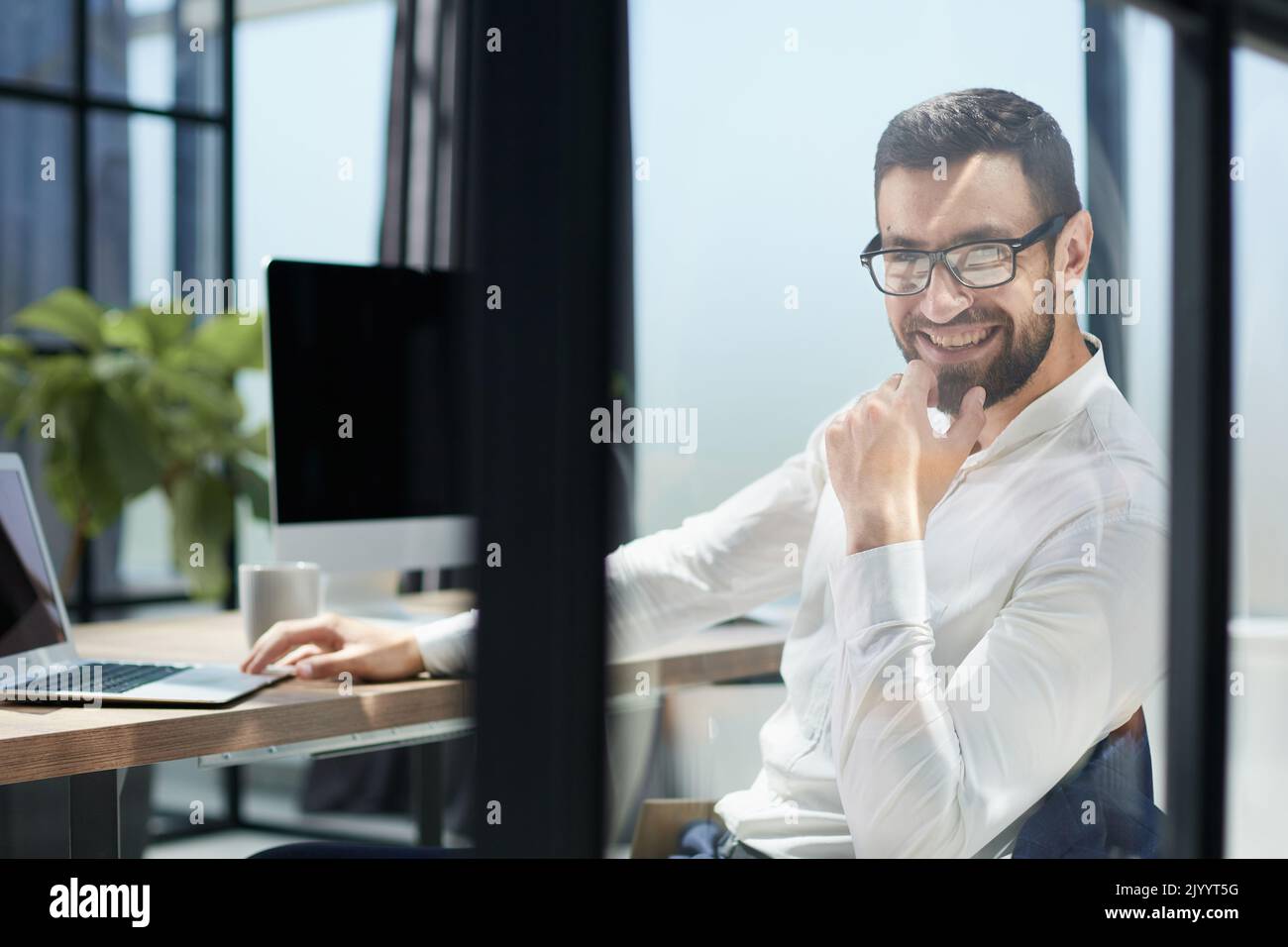 Businessman sitting at office desk working on laptop computer Stock ...