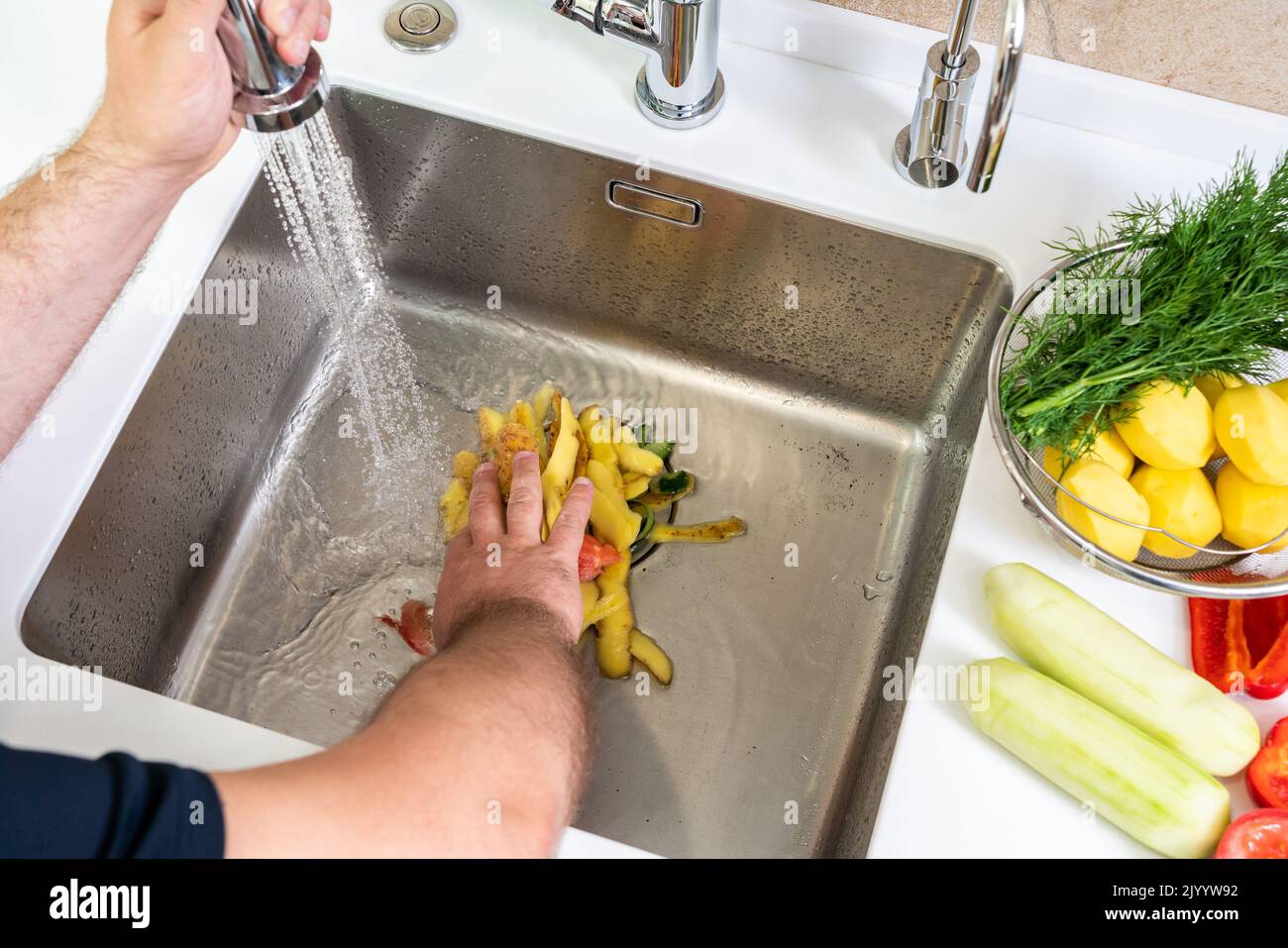 A hand shoves food waste into a disposer hole in the kitchen sink Stock ...