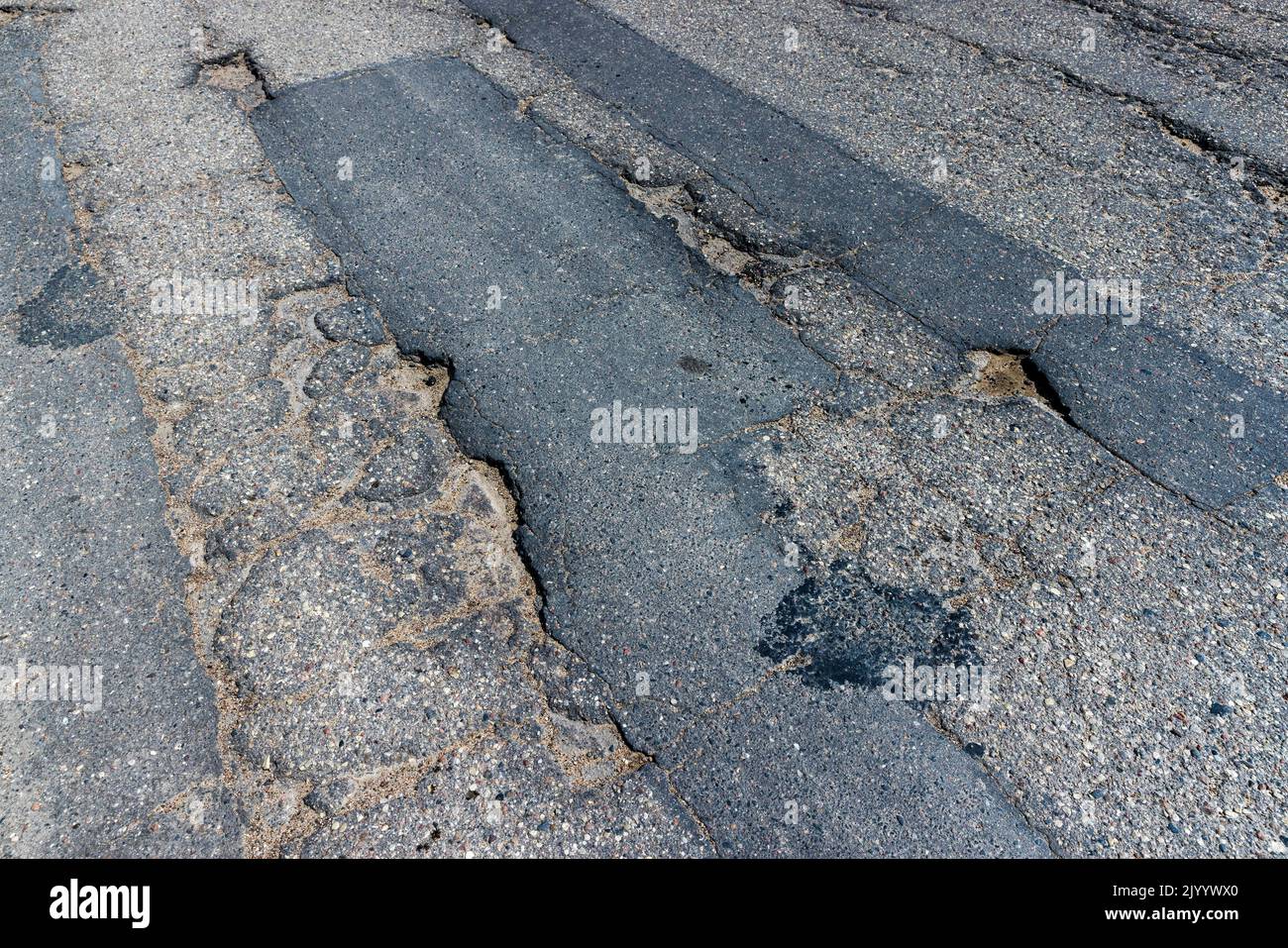 An old paved road with a lot of holes and damage, very poor quality of ...