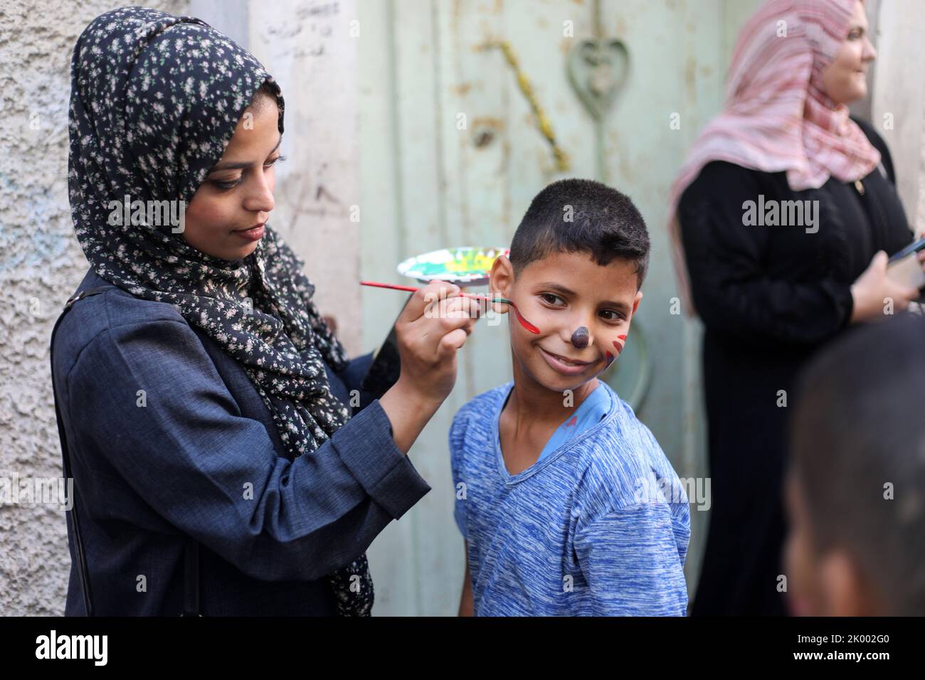 A Palestinian artist paints a child's face during the festival at ...