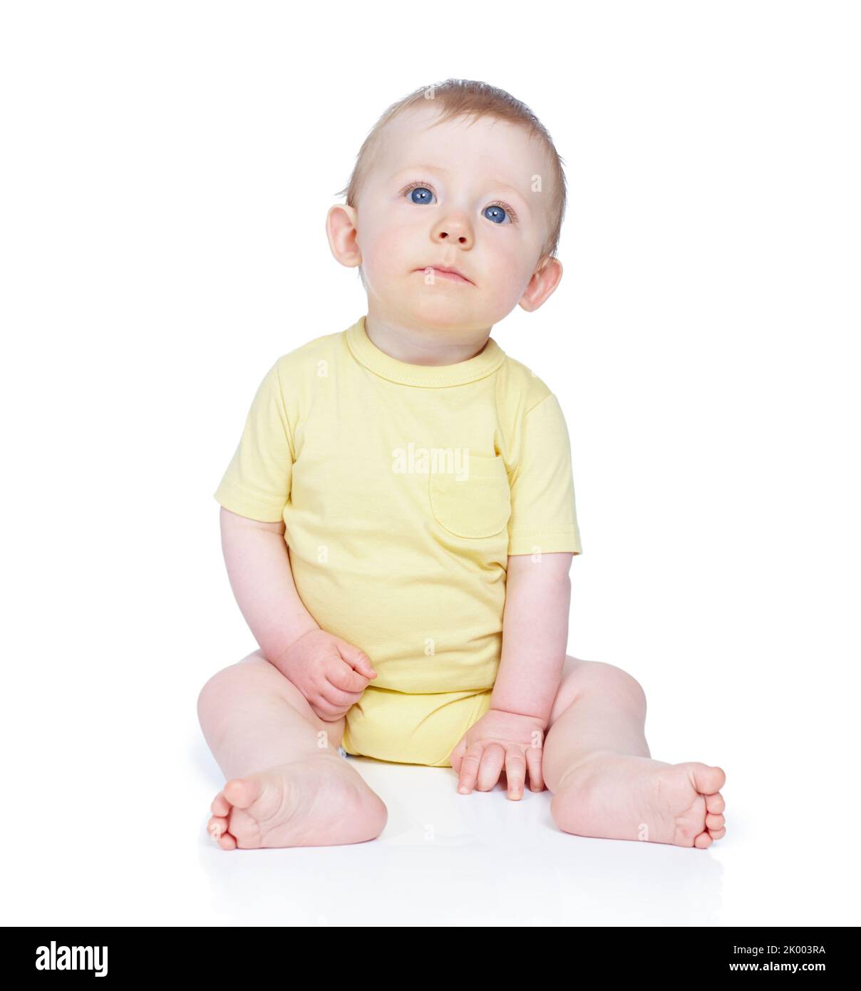 Dressed for a sunny day. A cute baby boy sitting on the floor against a ...