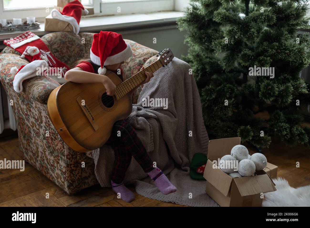 Child playing the guitar and singing near christmas tree Stock Photo ...