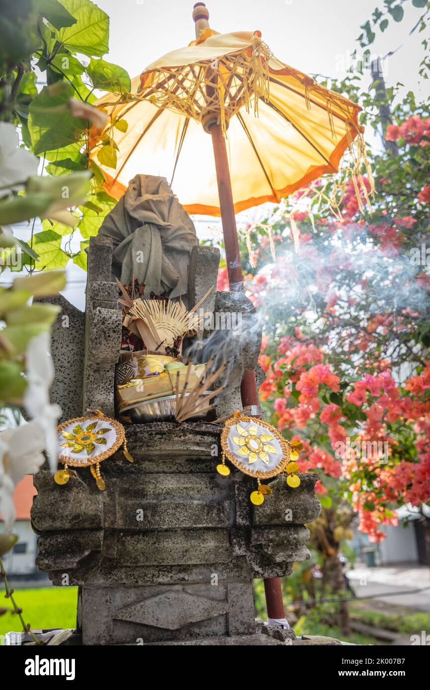 Balinese Hindu altar with yellow umbrella, offerings and burning ...