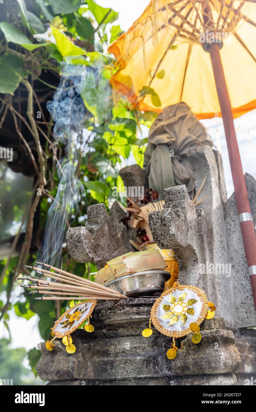 Balinese Hindu altar with yellow umbrella, offerings and burning ...