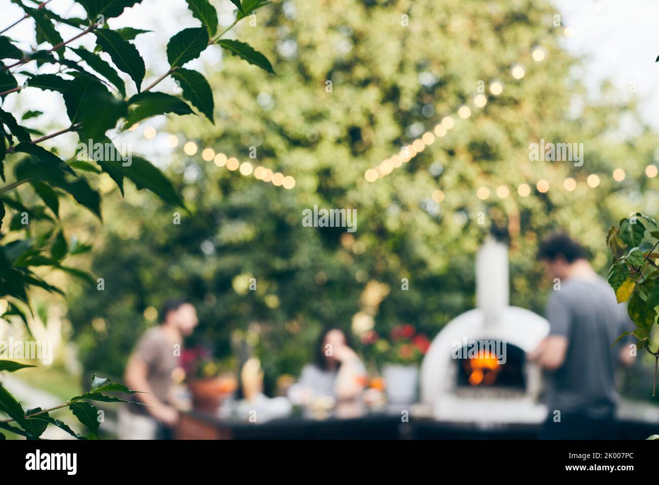 Friends in the backyard are cooking pizza in a wood-burning oven. A ...