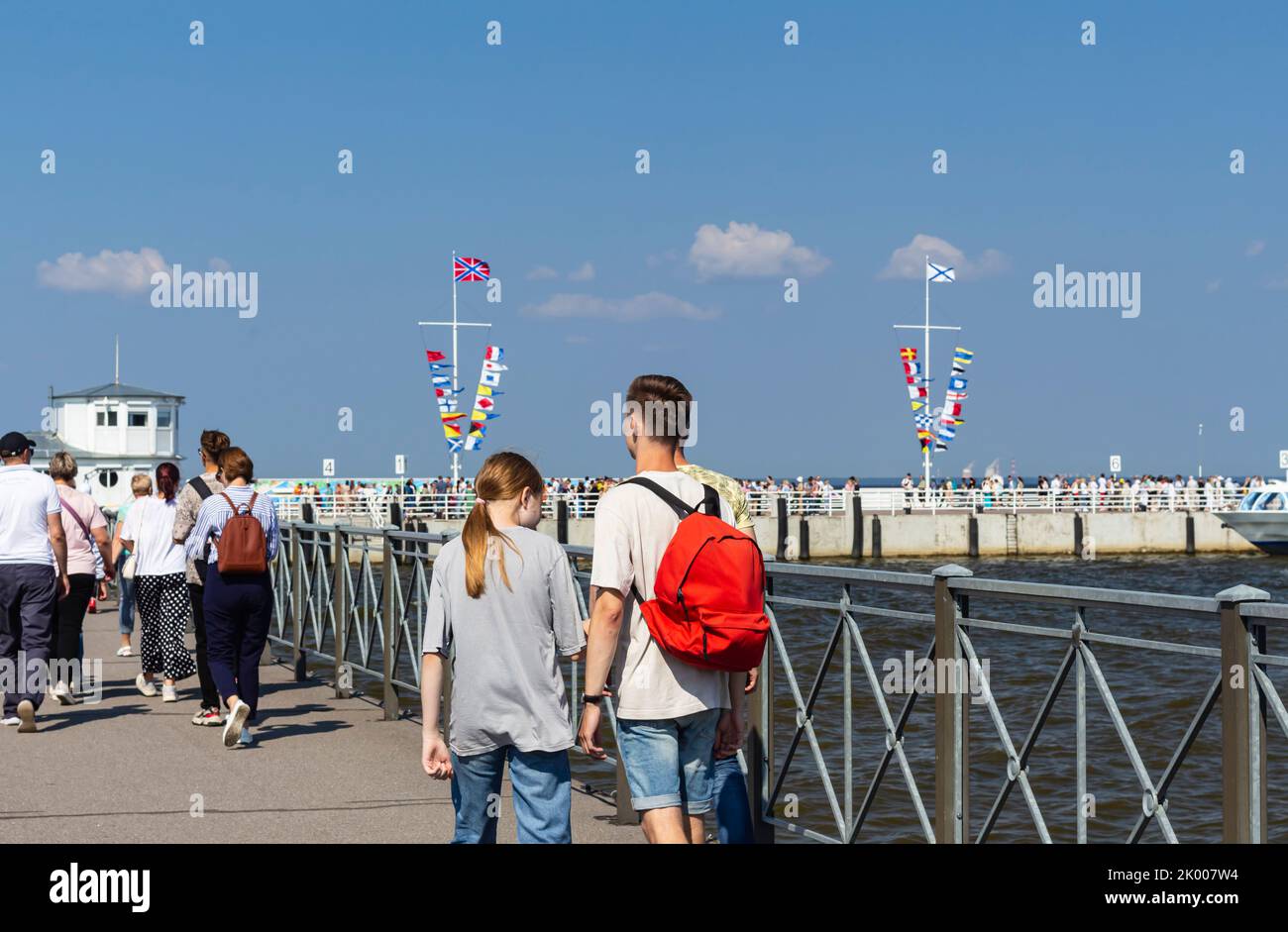 Crowd of tourists walk along pier to board ferry. Arrival of tourists ...