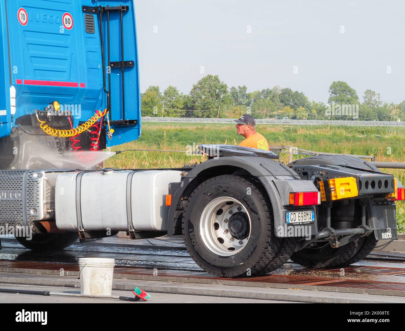 Man spraying exterior of blue semi truck using self service equipment ...