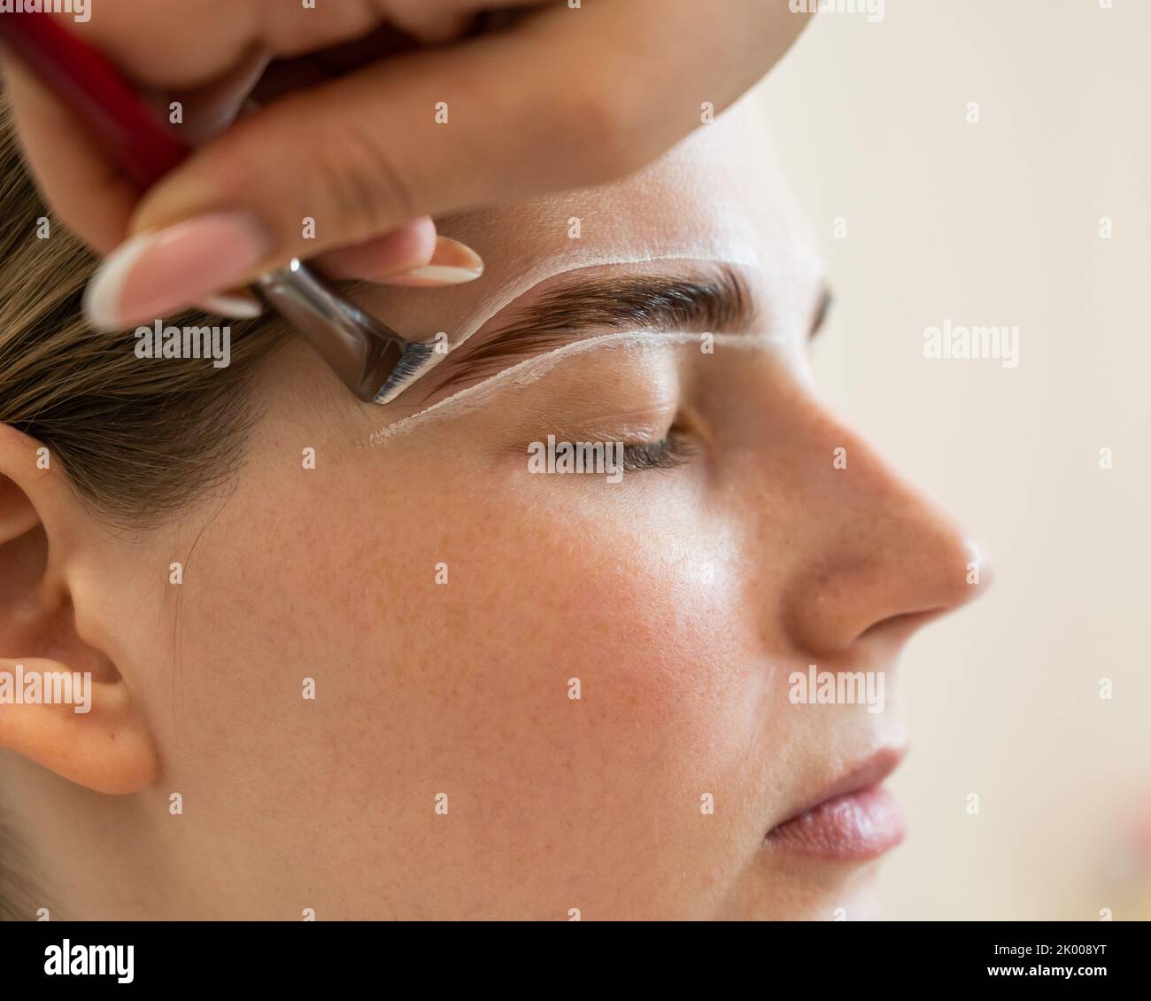 The master draws the shape of the eyebrows with white paint before ...