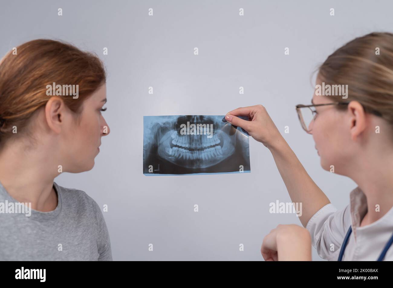 A woman doctor and a patient at the reception are discussing an x-ray ...