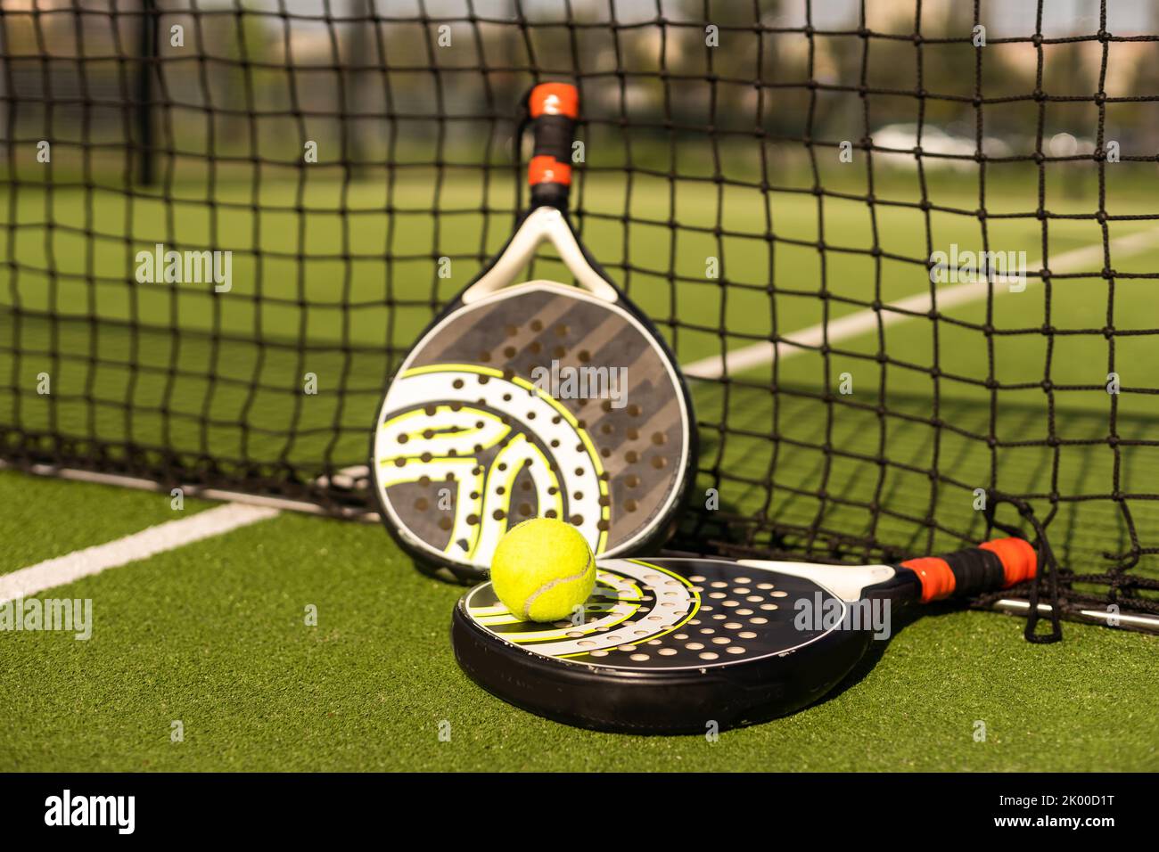 Yellow balls on grass turf near padel tennis racket behind net in green ...
