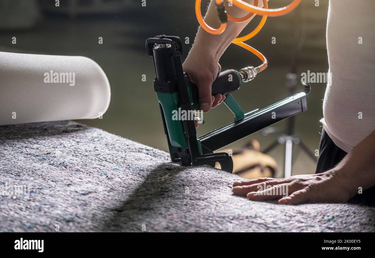 An employee holds in his hands an industrial air stapler for sheathe ...