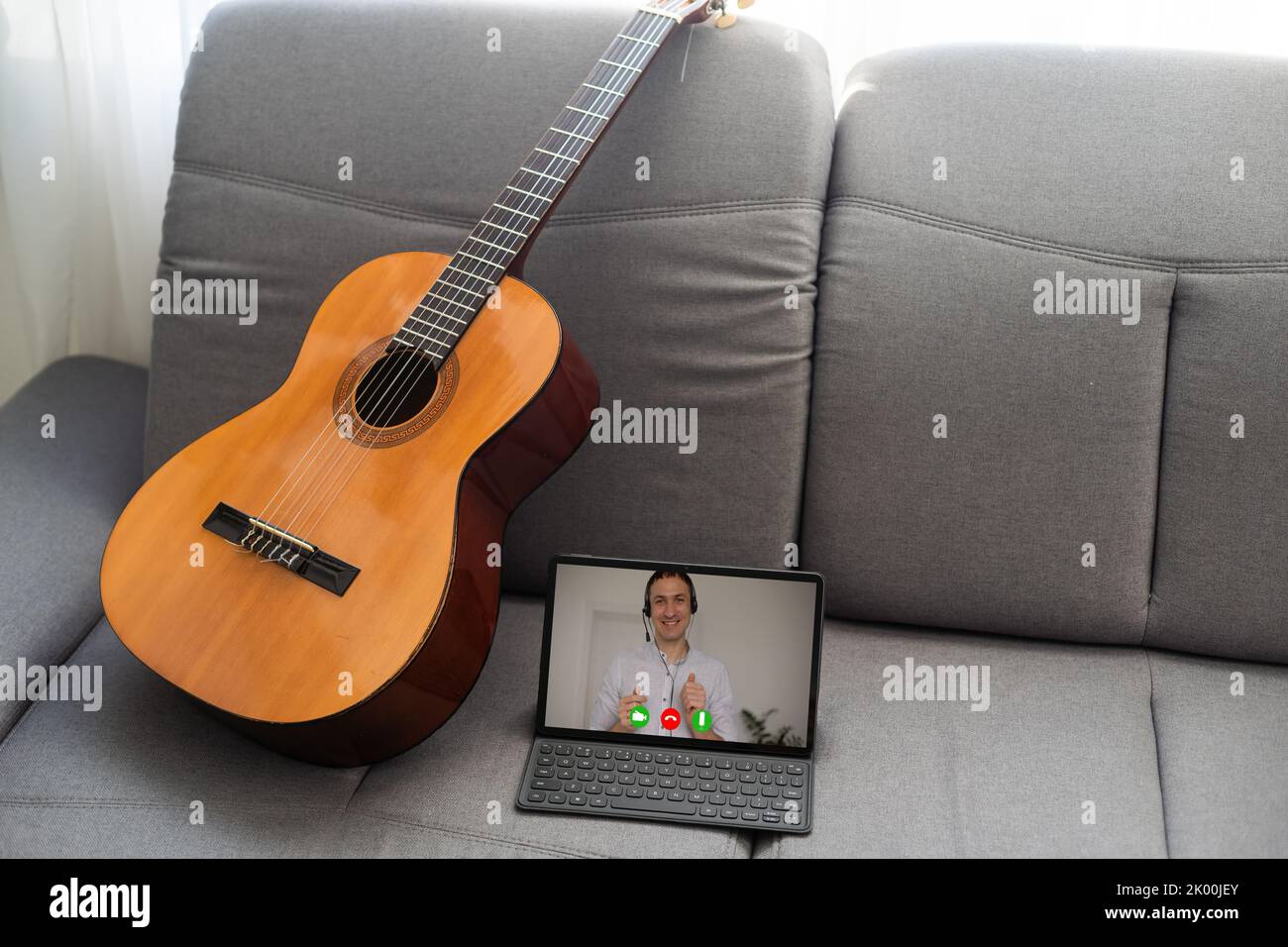 Acoustic guitar and digital tablet on a couch at cozy home background ...