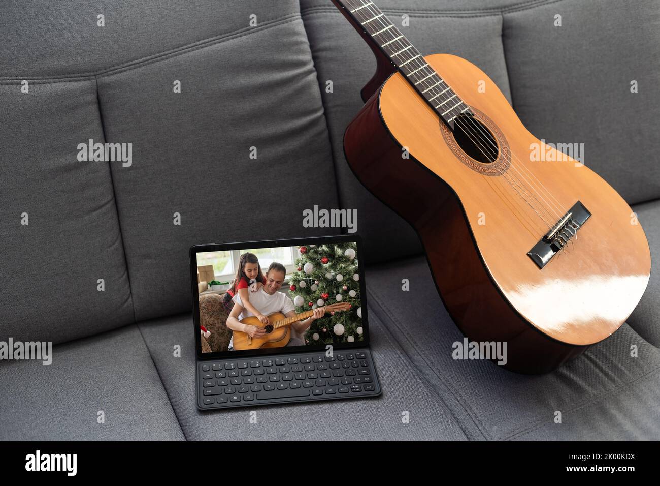 Acoustic guitar and digital tablet on a couch at cozy home background ...