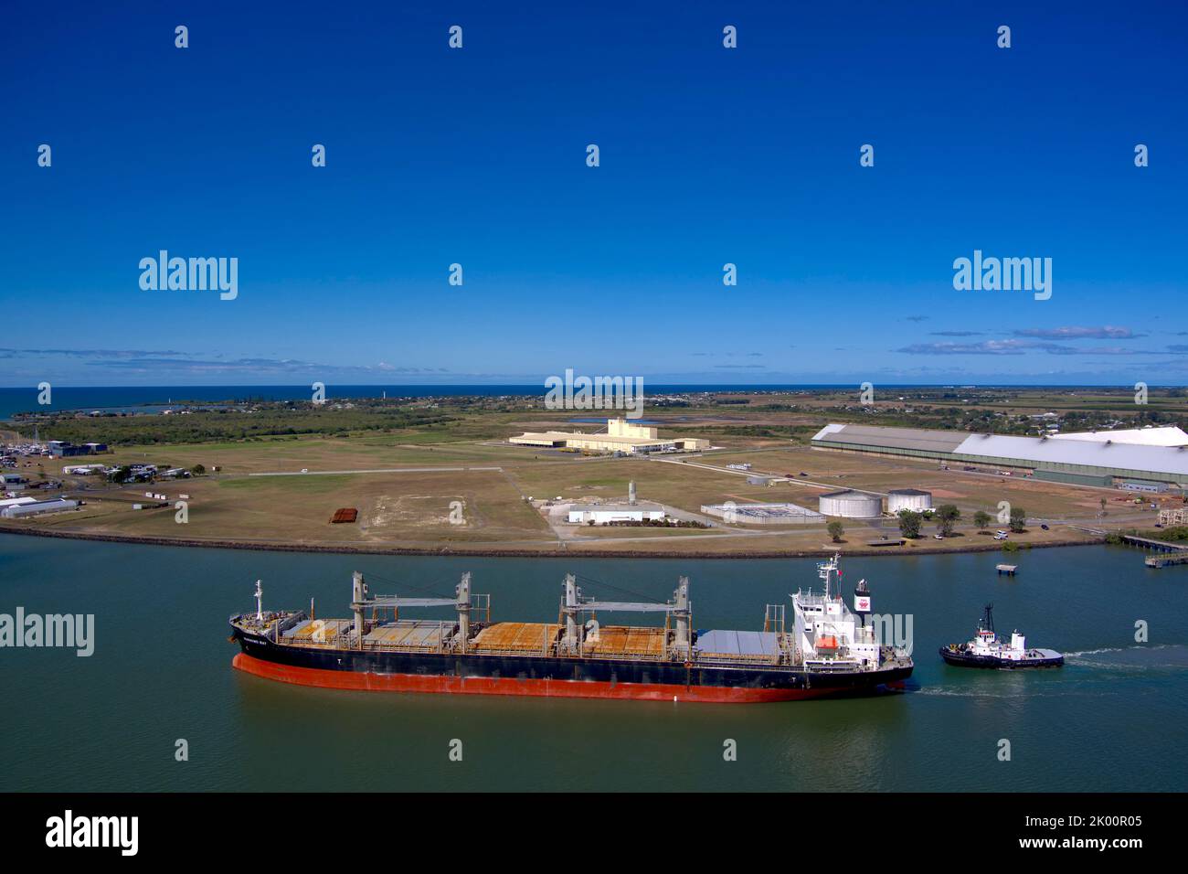 Aerial view of a large cargo ship being guided by a tugboat near ...
