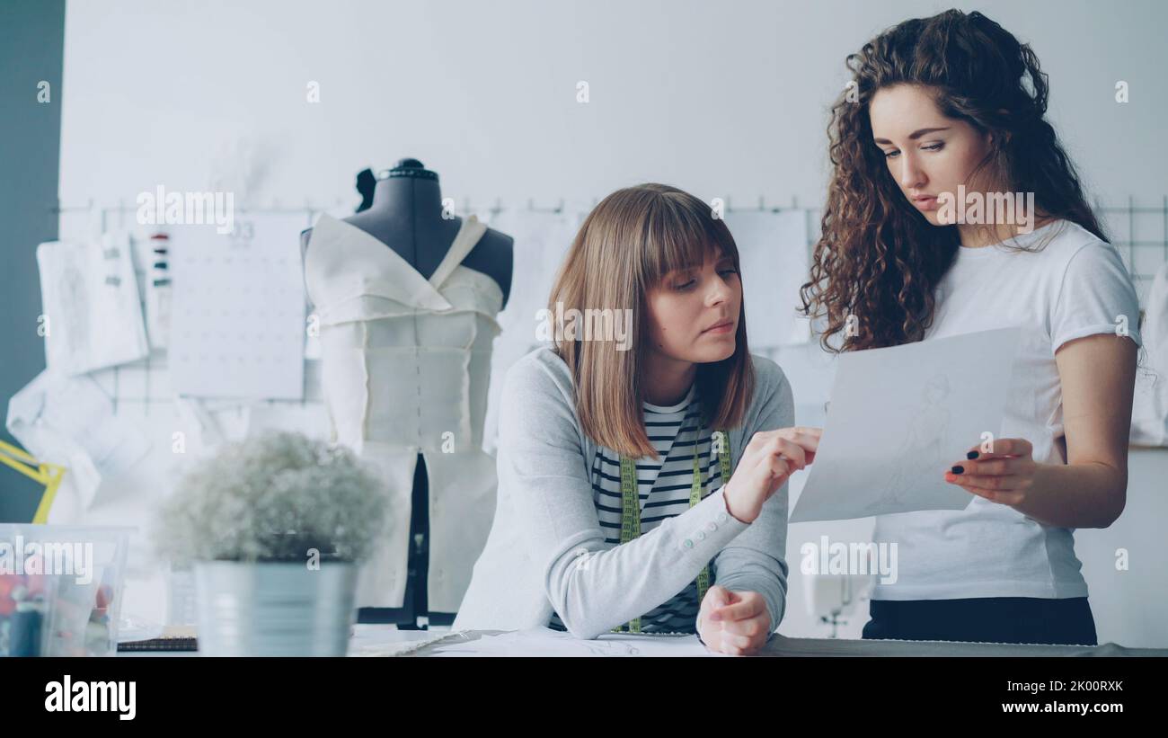 Professional female fashion designers are looking at sketch and ...
