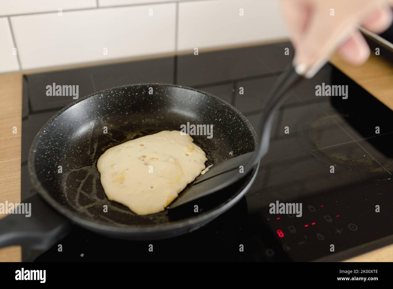 flipping a partially cooked pancake in a fry pan on a stove Stock Photo ...