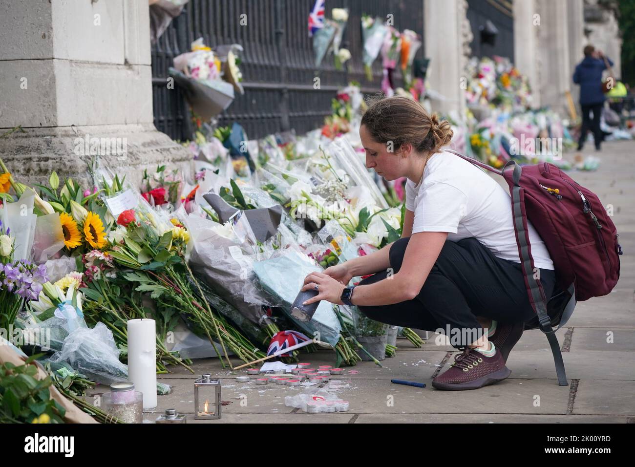 A woman lights a candle by the railings at Buckingham Palace, London ...
