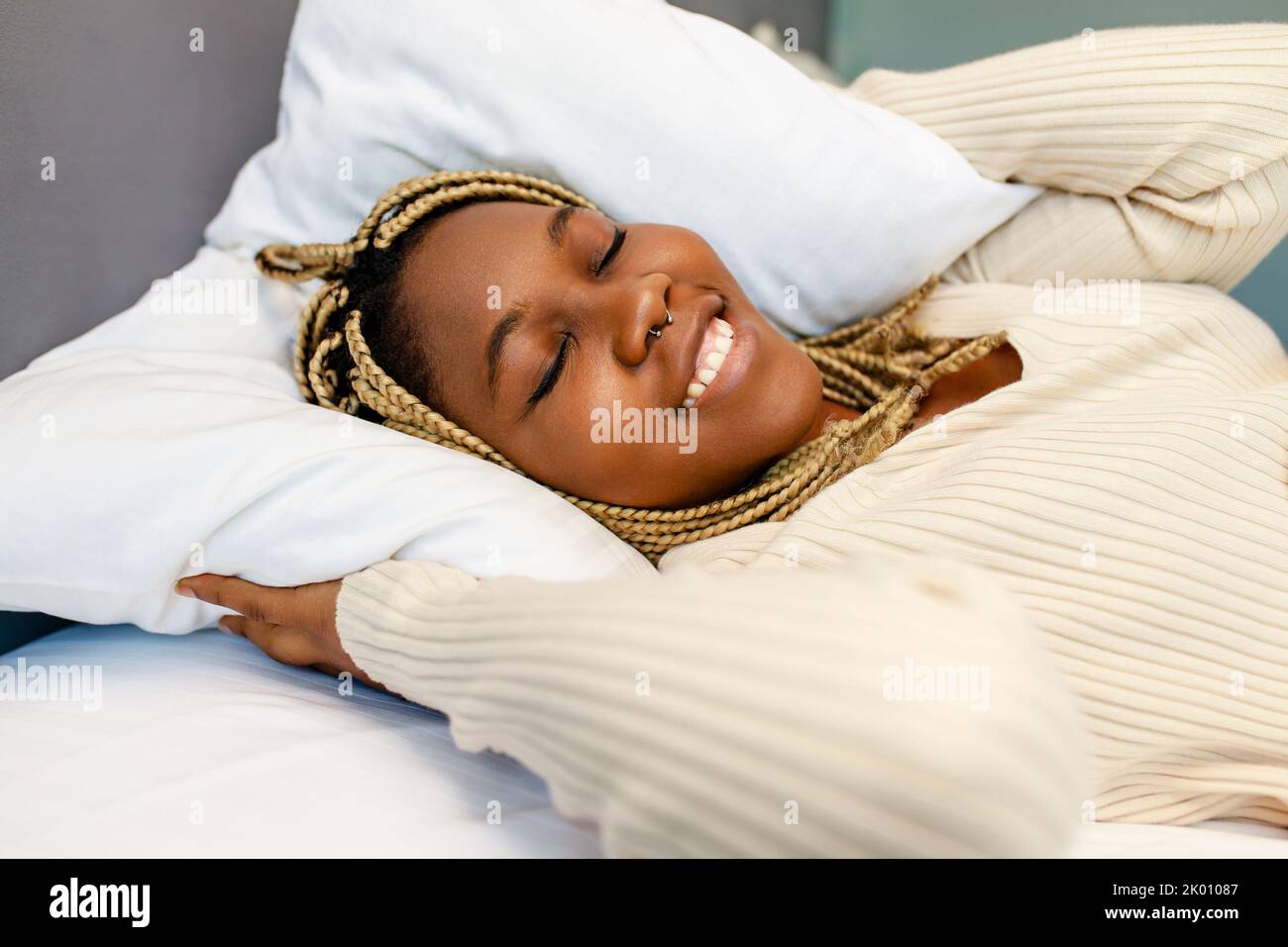 Afro american female keeping eyes closed while awake at the bedroom ...