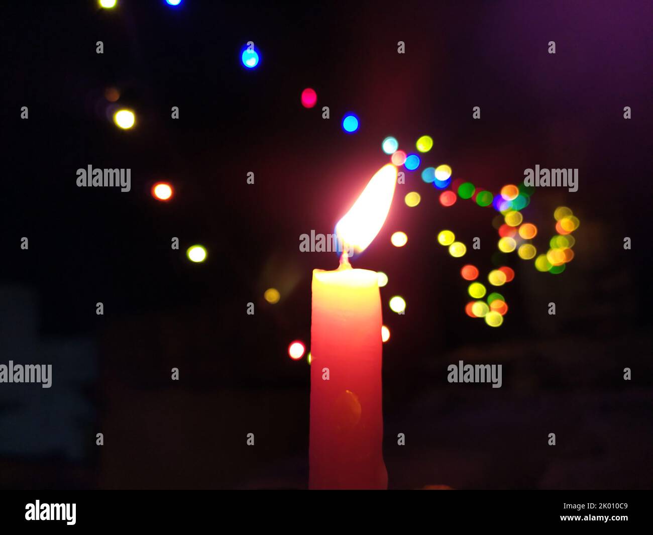 A CANDLE FLAME GIVE LIGHT IN DARK NIGHT WITH LIGHT BILINKING BEHIND ...