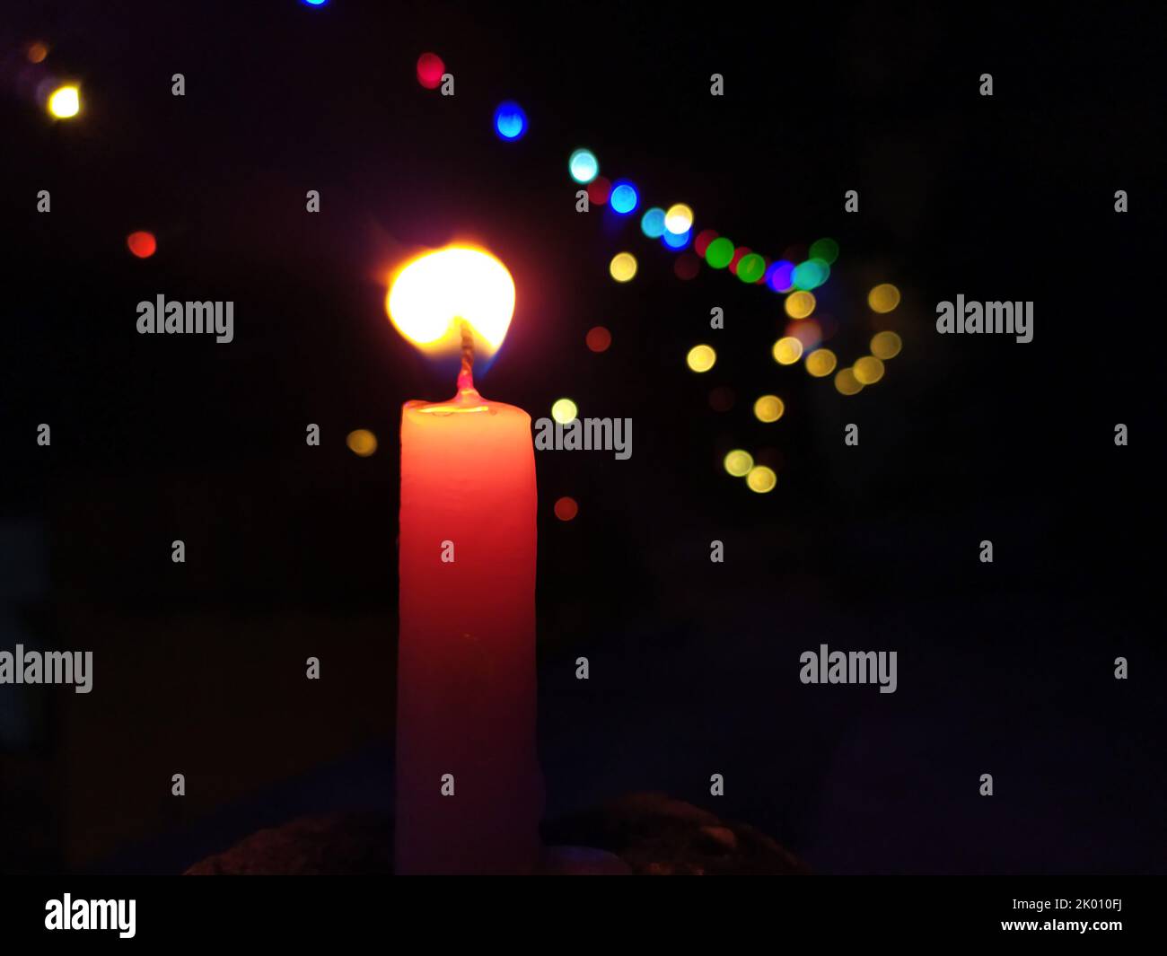 A CANDLE FLAME GIVE LIGHT IN DARK NIGHT WITH LIGHT BILINKING BEHIND ...