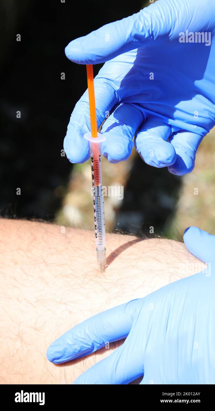 thigh of boy and gloved hand during insulin injection due to diabetes ...