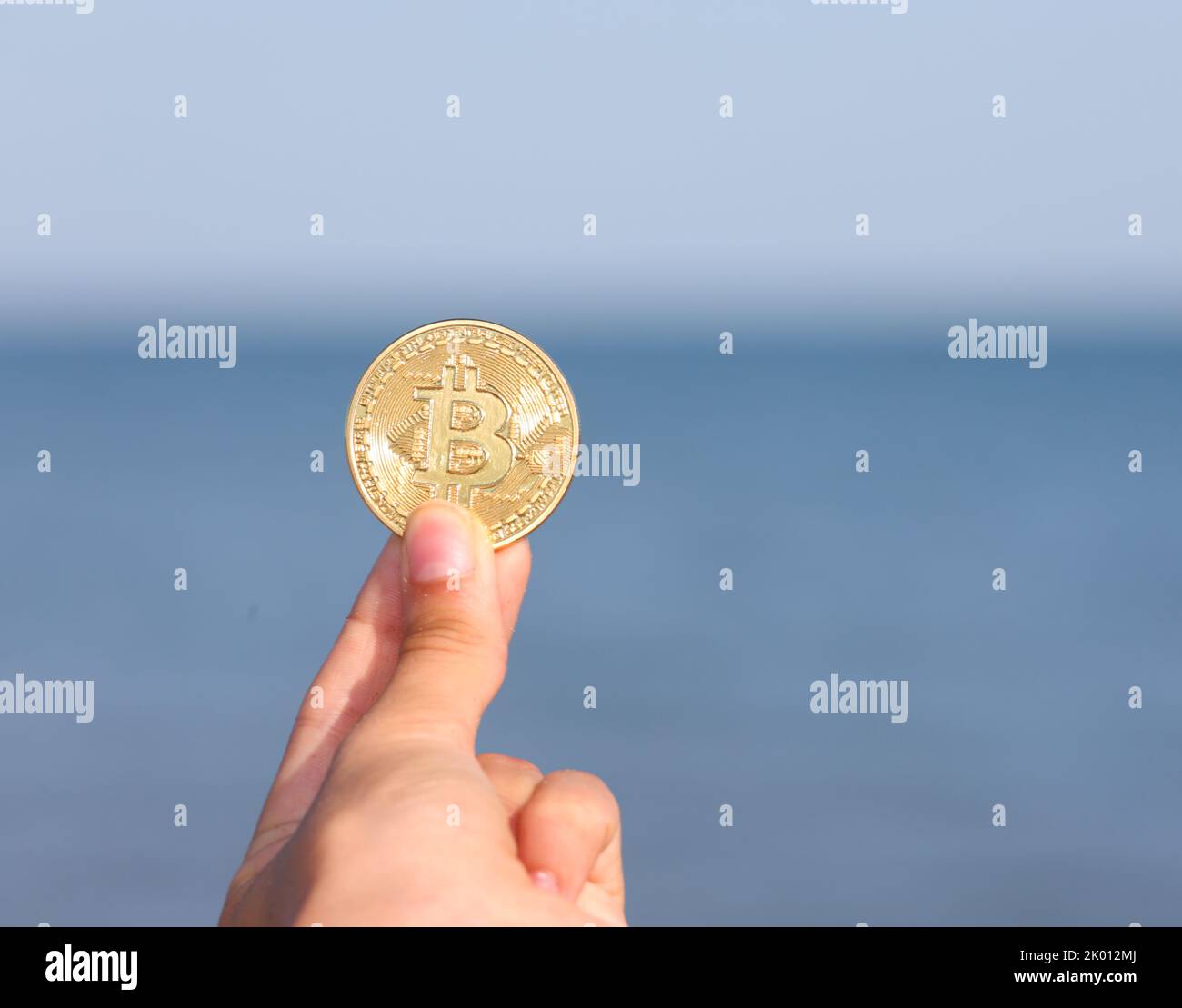 young hand holding a golden coin with the letter B indicating the ...