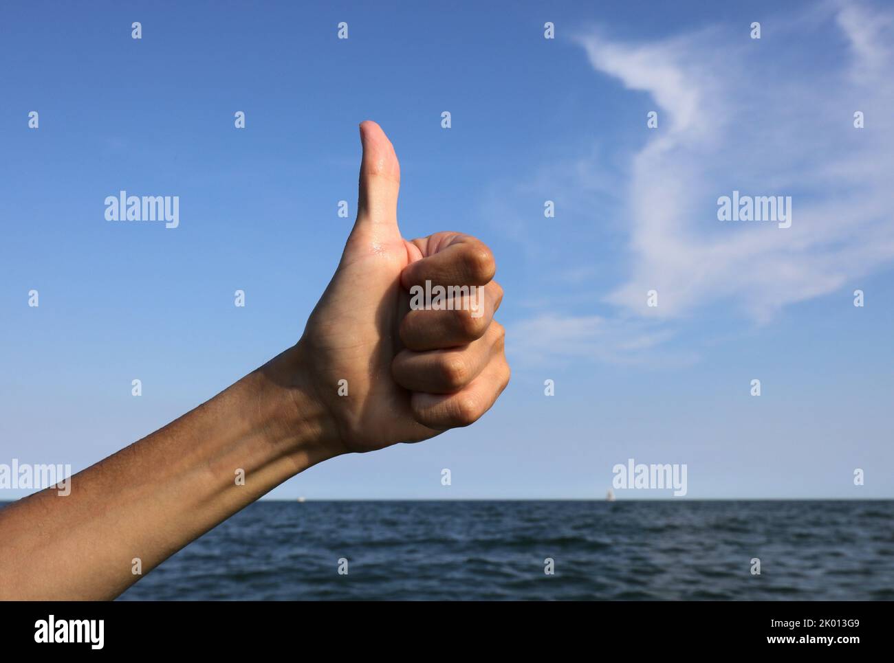 hand with thumb up pointing up ok sign all right or success and the sea Stock Photo - Alamy