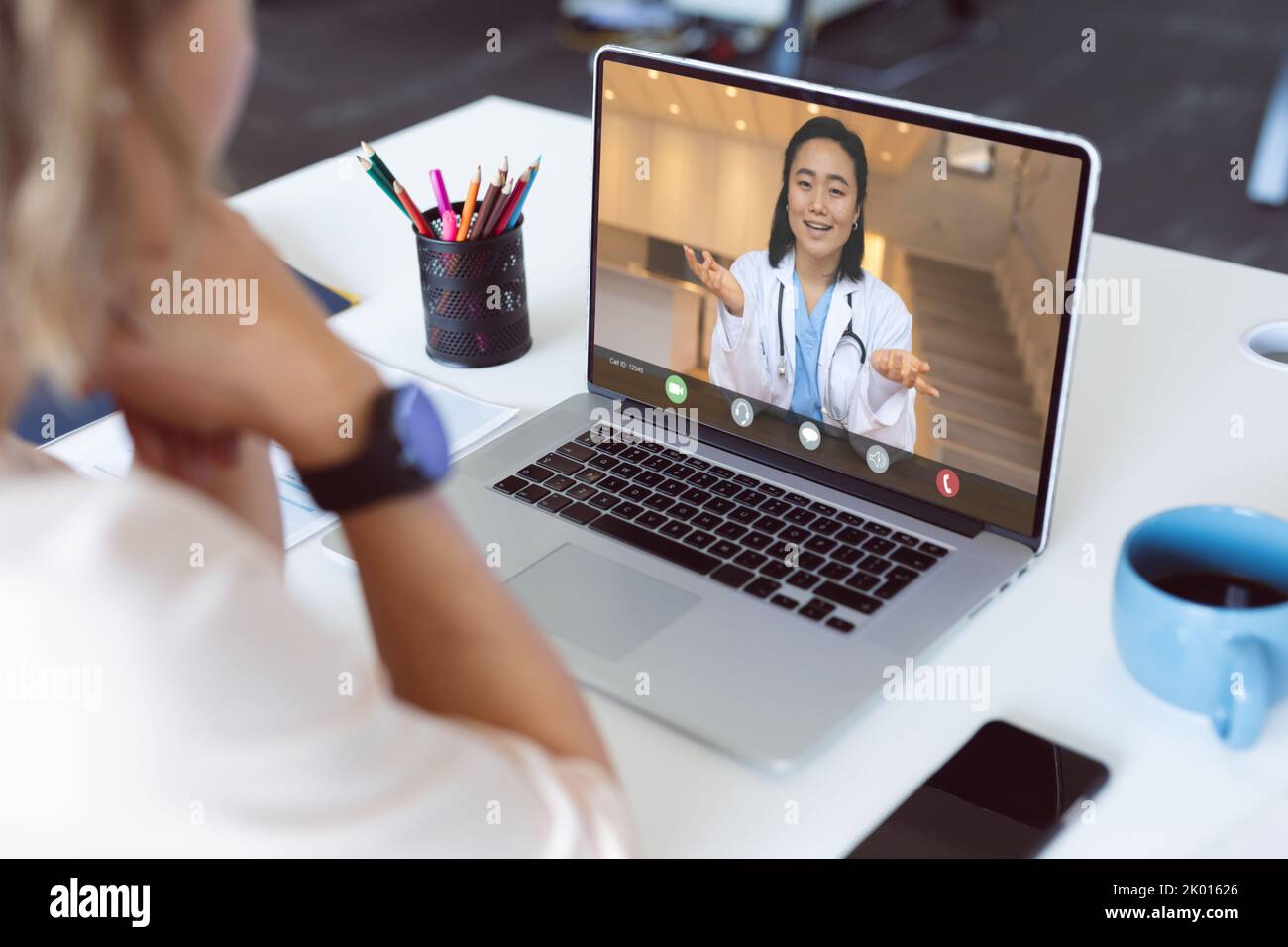 Over shoulder view of woman having laptop video call with smiling asian ...