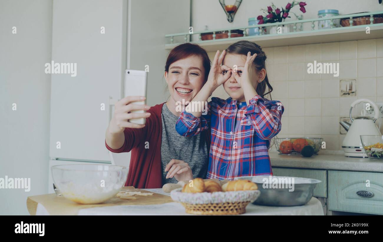 Smiling mother together with funny cute daughter taking selfie photo ...