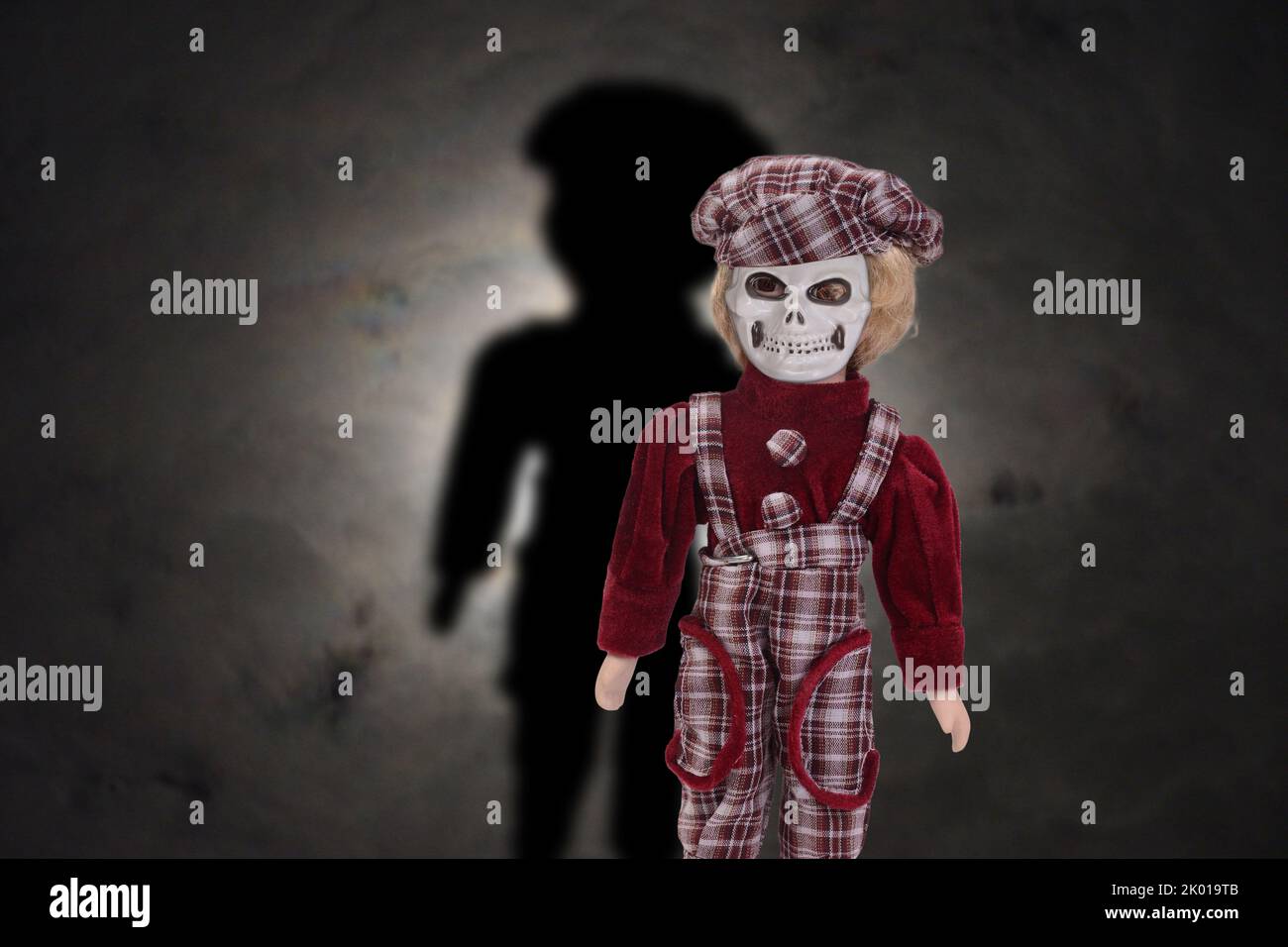 Doll in red costume wearing skull mask standing with black shadow in ...